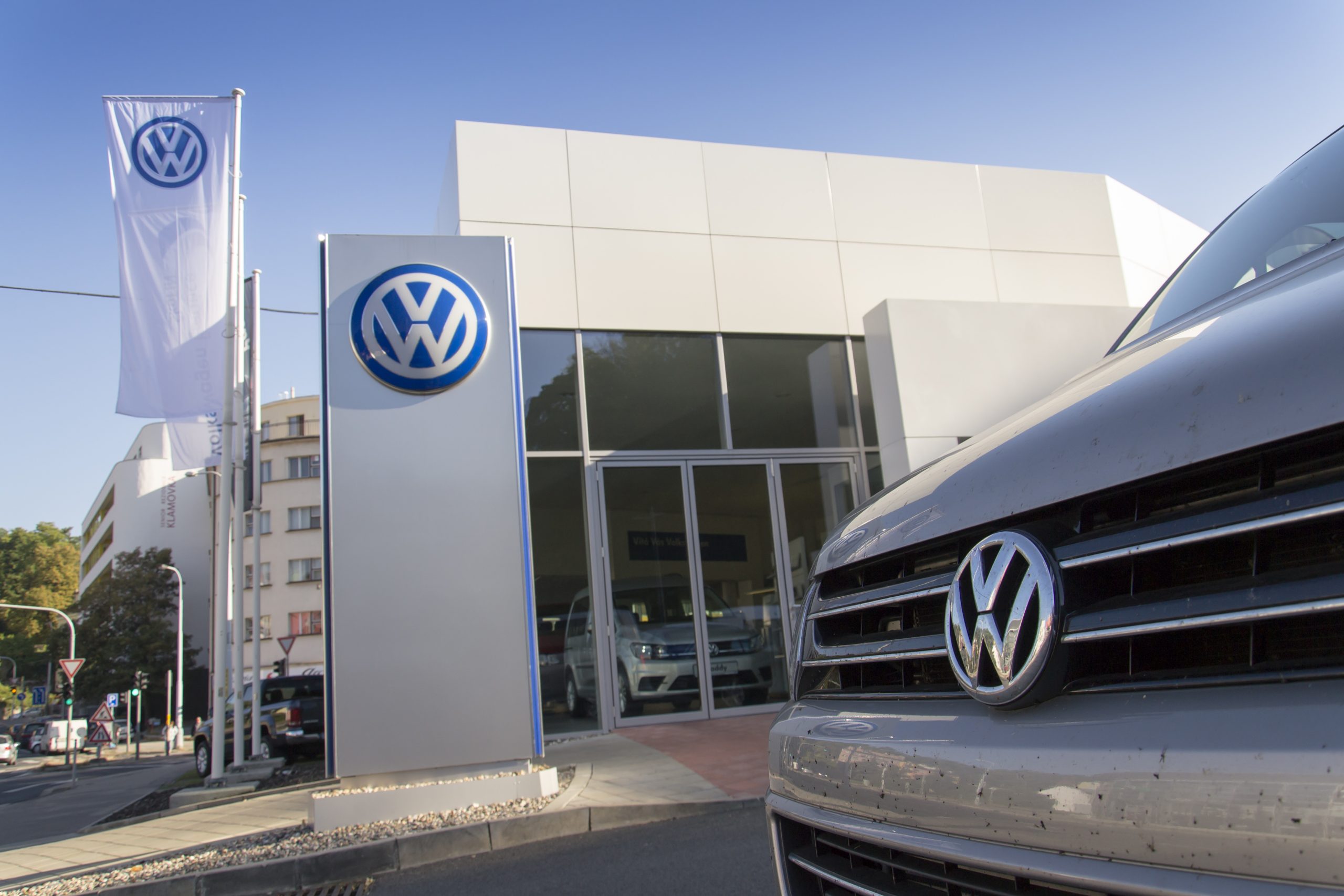 Car with Volkswagen logo in front of dealership building | Fynsa